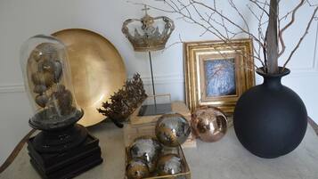 Conjunto de objetos decorativos incluindo uma cúpula de vidro, um prato dourado, um vaso preto e uma moldura com fotografia.