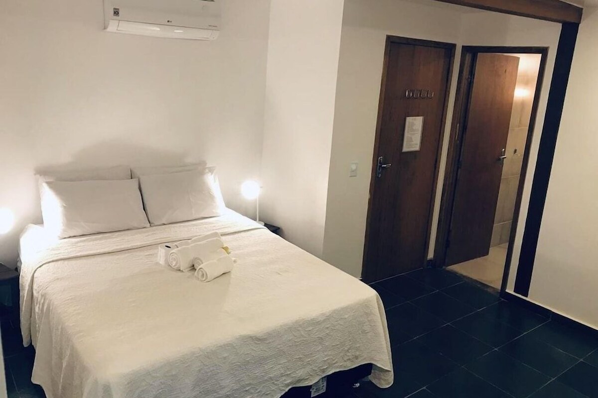 Quarto de hotel com cama, guarda-roupa e ar condicionado.