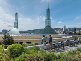 Terraço no telhado com área de estar externa e vista para dois edifícios altos.