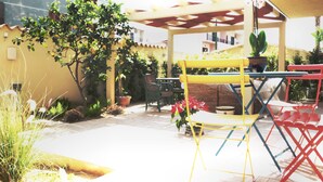 Um pátio com uma cadeira dobrável amarela, uma mesa e vasos de plantas.