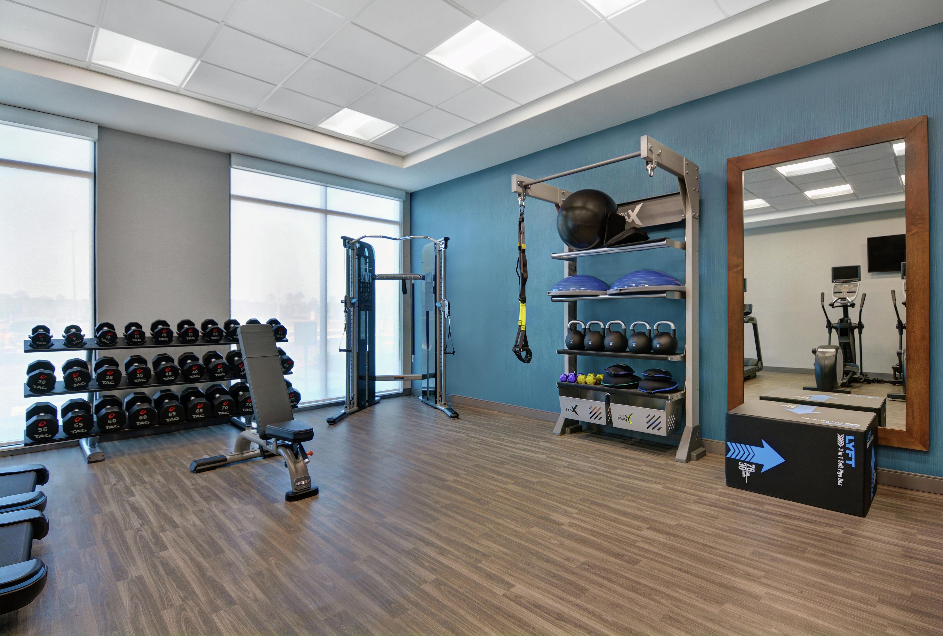 Academia com equipamentos de musculação, halteres e aparelhos de cardio.