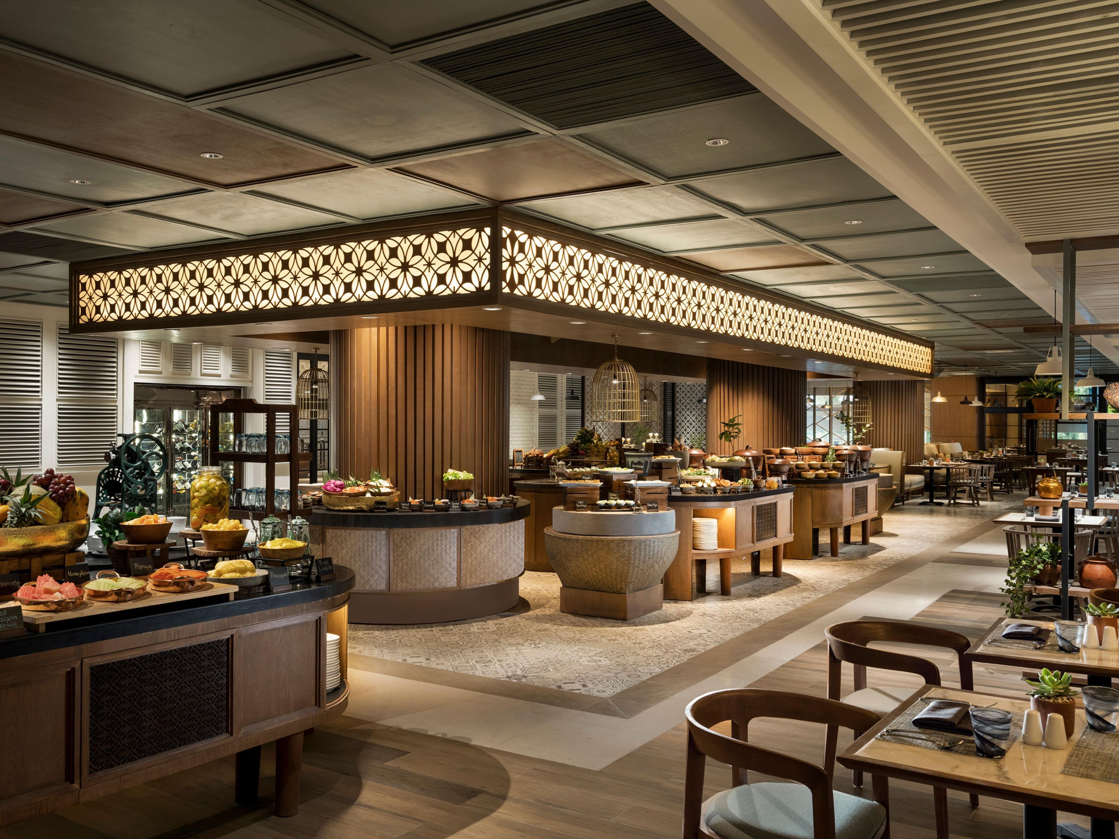 Um saguão de hotel moderno com área de bar central, espaços para sentar e teto decorativo.