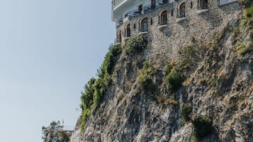 Um edifício costeiro com uma escadaria que leva a uma varanda, com vista para o mar.