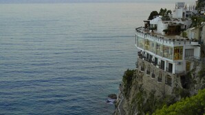 Hotel na encosta de um penhasco, com várias varandas viradas para o mar.