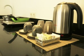 Uma bancada de cozinha com uma chaleira, xícaras e um escorredor de louça.