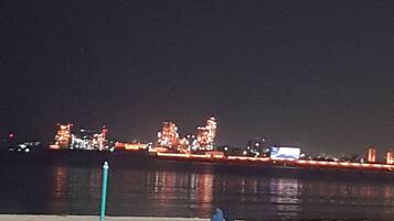 Vista noturna de uma praia com o horizonte urbano ao fundo.