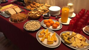 Uma mesa de buffet com diversos alimentos, incluindo doces, frutas e um bolo.
