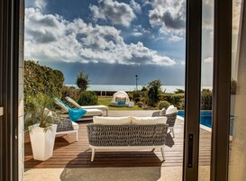 Um terraço com móveis para área externa, piscina e vista para o mar.