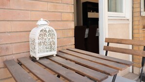 Um banco de madeira com um candeeiro branco decorativo em frente a uma parede de tijolos.