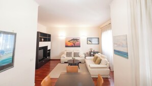 Uma sala de estar moderna com um sofá, mesa de centro e televisão de tela plana.