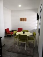 Uma pequena sala de jantar com uma mesa redonda, quatro cadeiras e um vaso de planta.