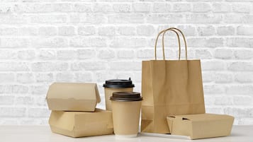 Paredes de tijolos brancos com caixas de papelão e sacos de papel.