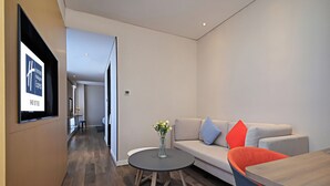 Quarto de hotel moderno com um sofá, uma mesa redonda e um vaso de flores.