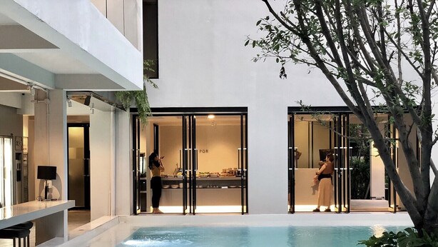 Uma área interna de piscina moderna com portas de vidro que dão para uma cozinha e uma sala de jantar.