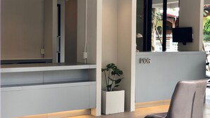 Um interior moderno com um espelho grande, uma área de estar com uma poltrona e um balcão com uma placa que diz 'POR'.