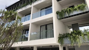 Edifício com várias andares e varandas decoradas com vegetação.