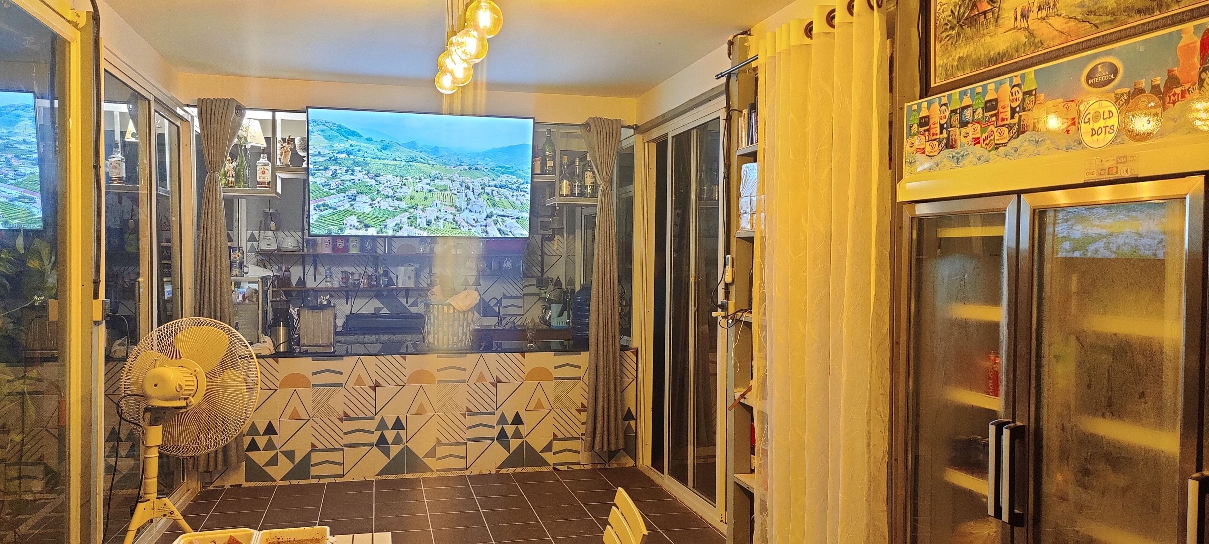 Uma cozinha moderna com uma televisão grande, um ventilador e uma geladeira.