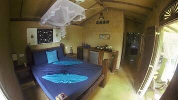 Quarto com cama, mesas de cabeceira, ventoinha no teto e apoio para objetos.