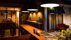 Uma cozinha moderna com um balcão de madeira comprido, iluminação pendente e um espaço de jantar com bancos.