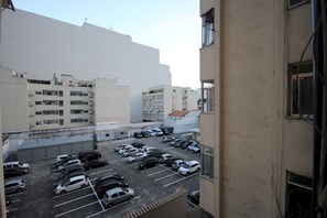 Um estacionamento com vários carros e um prédio com varandas ao fundo.