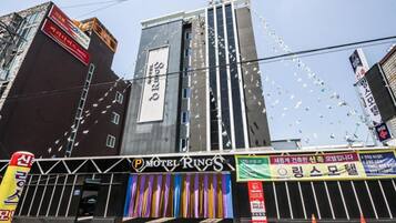 Um edifício com uma placa que diz 'Motel Rings' e uma grande placa vertical com texto em coreano.
