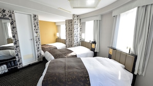 Quarto de hotel com duas camas, um guarda-roupa, uma casa de banho e uma janela grande com cortinas.