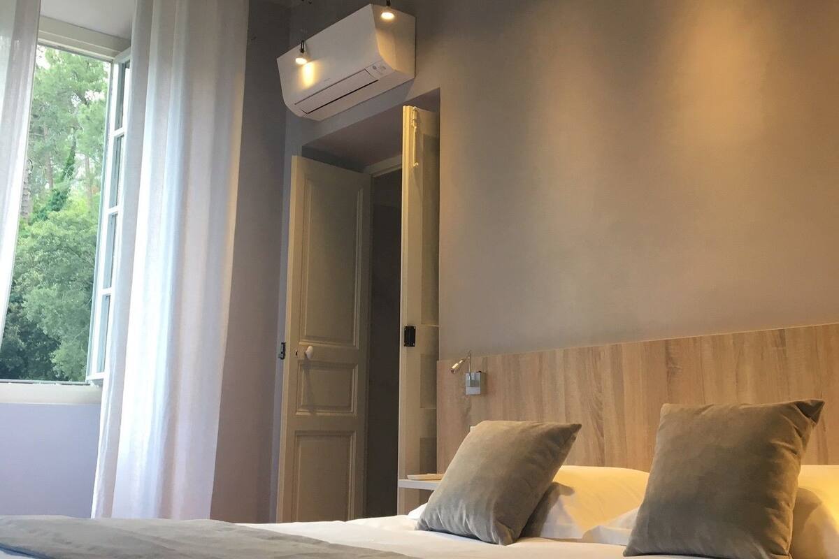 Quarto com uma cama grande, cabeceira de madeira e um ar condicionado na parede.