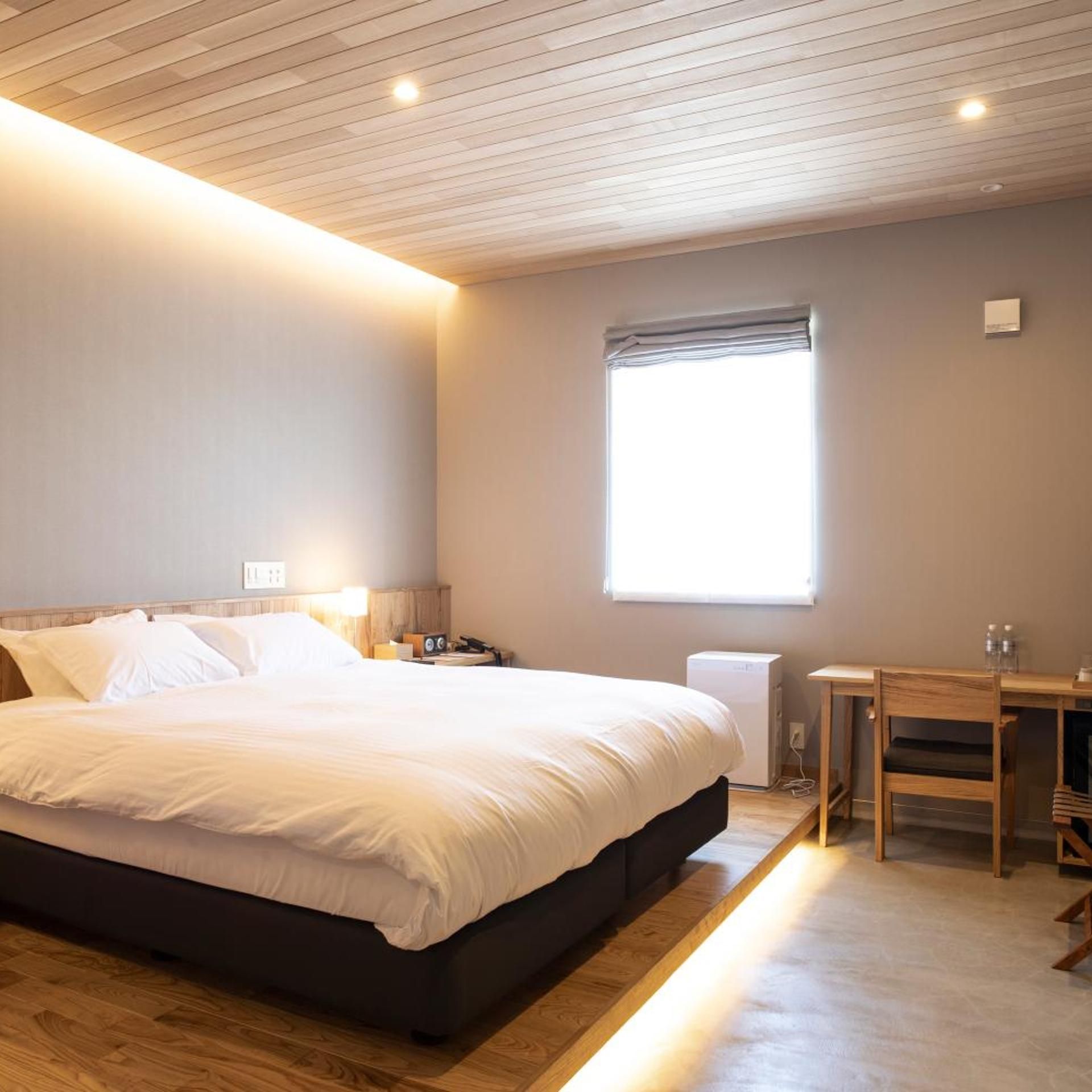 Quarto moderno com uma cama grande, mesas de cabeceira, escrivaninha e janela.