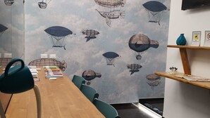 Uma sala de conferências com uma longa mesa de madeira, cadeiras azul-turquesa e um mural na parede com balões de ar quente.