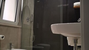 Uma casa de banho moderna com cabine de chuveiro em vidro, uma banheira independente e um lavatório suspenso.