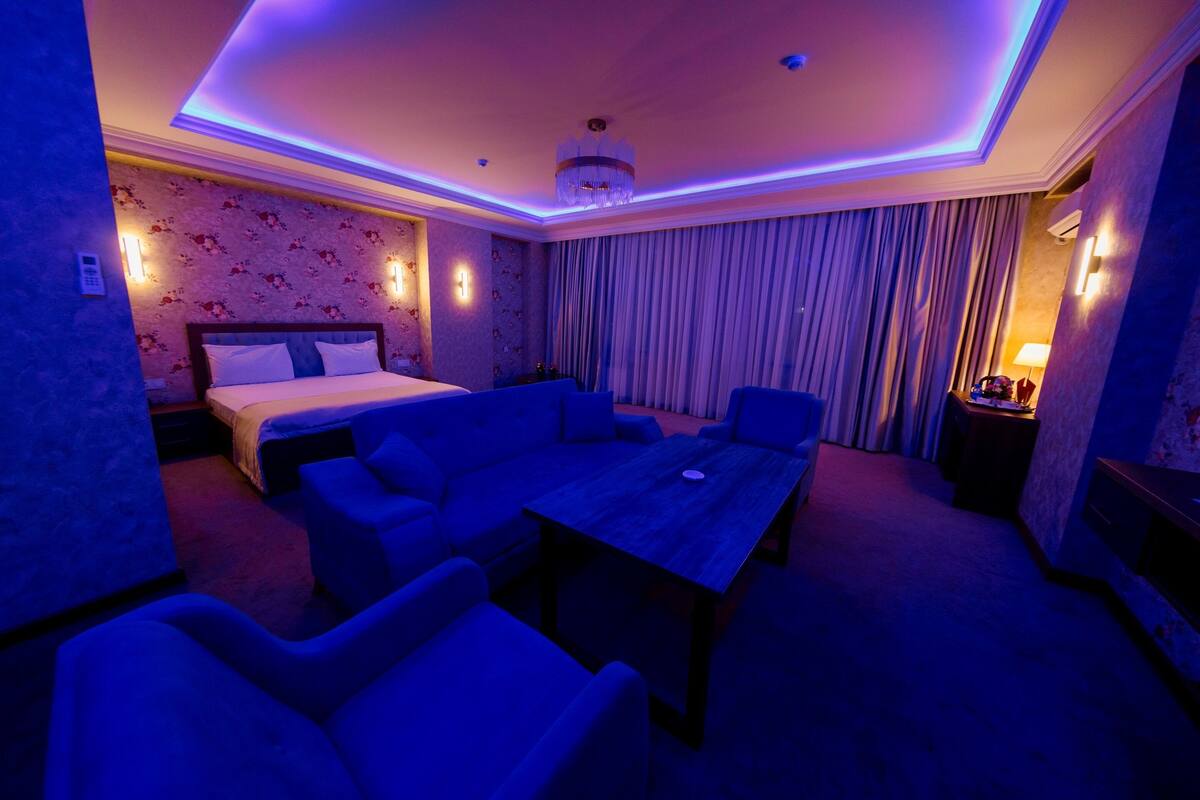 Quarto de hotel moderno com cama, sofá e mesa de jantar.