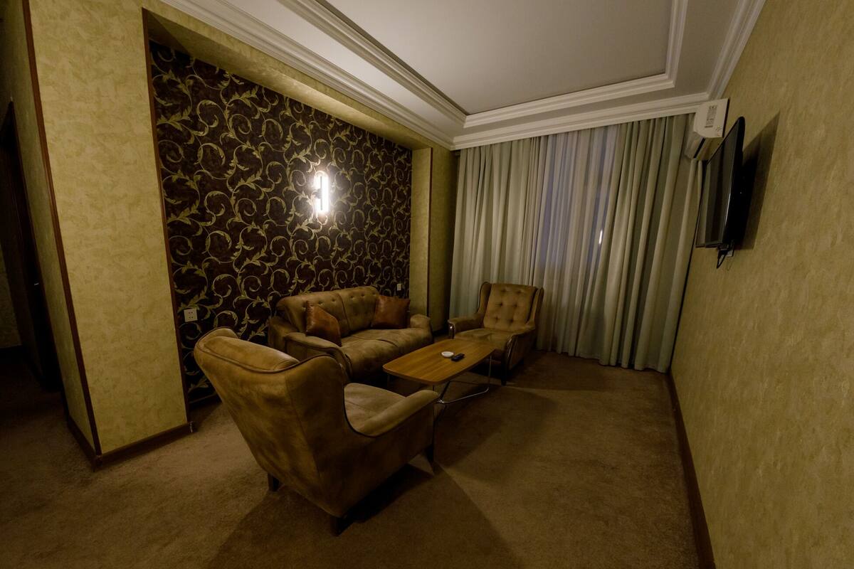 Um quarto aconchegante com sofá, poltronas e mesa de centro.