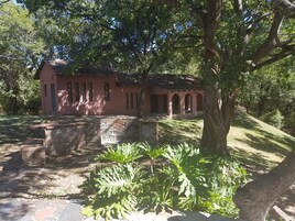 Um edifício rosa com fachada de tijolos, rodeado por árvores e um caminho de pedra.