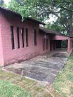 Um edifício cor-de-rosa com um pátio de pedra e uma área coberta.