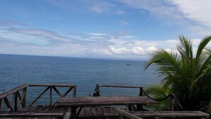 Um deck de madeira com vista para o oceano e um barco ao longe.