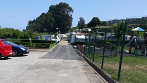 Uma área de estacionamento com carros compactos e cerca verde.