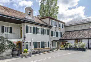 Um edifício europeu tradicional com um letreiro de restaurante, mesas ao ar livre e uma torre de sino.