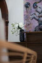 Uma escrivaninha de madeira com um vaso de flores brancas e um livro.