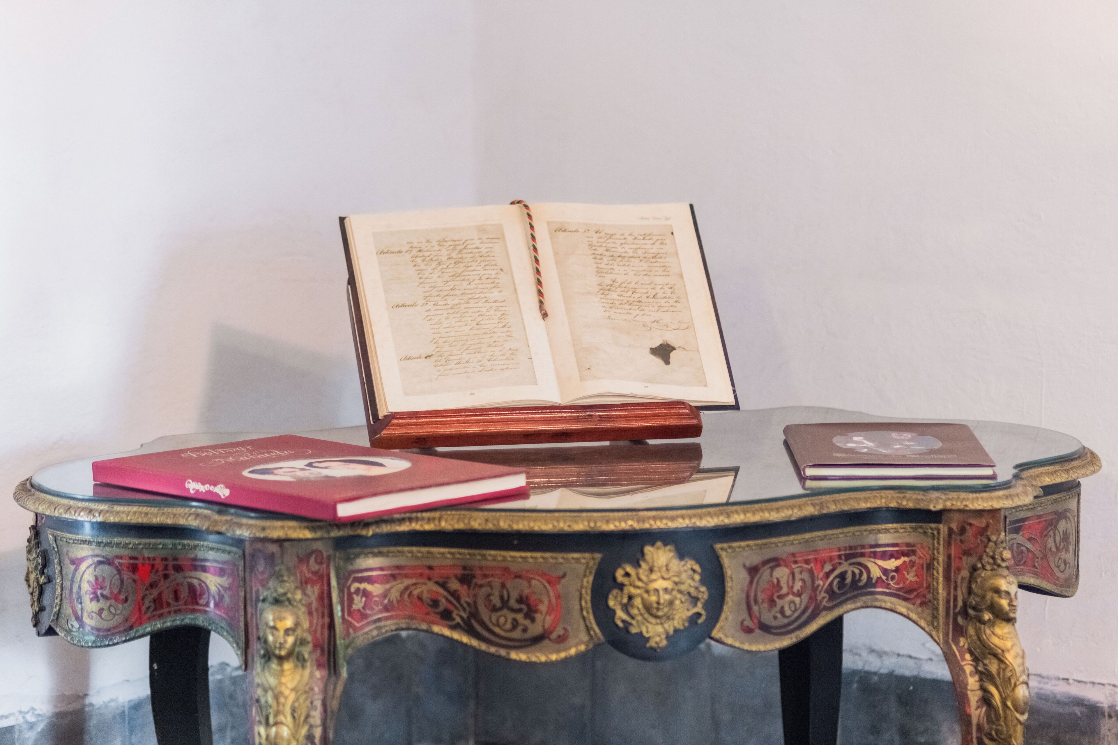 Uma mesa elaborada com um livro aberto e dois livros em cima.