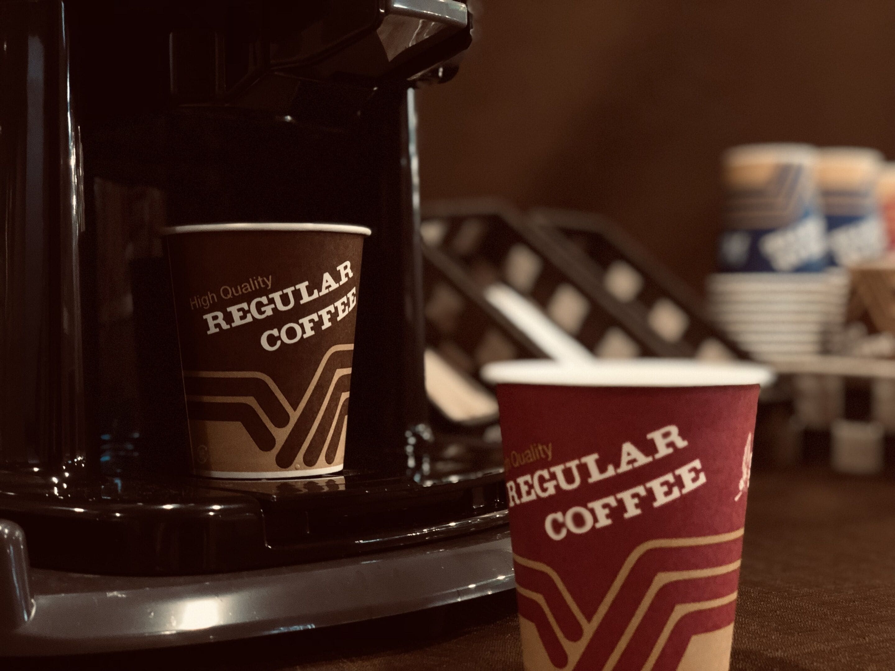 Máquina de café com uma xícara descartável etiquetada com 'Regular Coffee'.