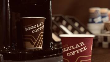 Máquina de café com uma xícara descartável etiquetada com 'Regular Coffee'.