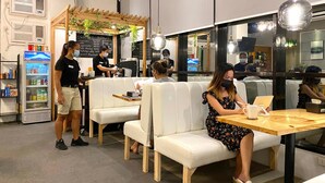 Um café moderno com assentos acolchoados em branco, uma máquina de café e um quadro de cardápio.