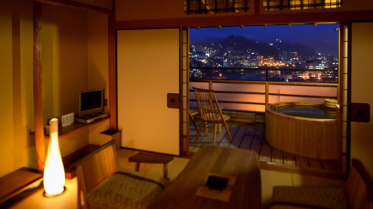 Quarto com vista para a cidade, banheira de hidromassagem, televisão e porta deslizante tradicional japonesa.