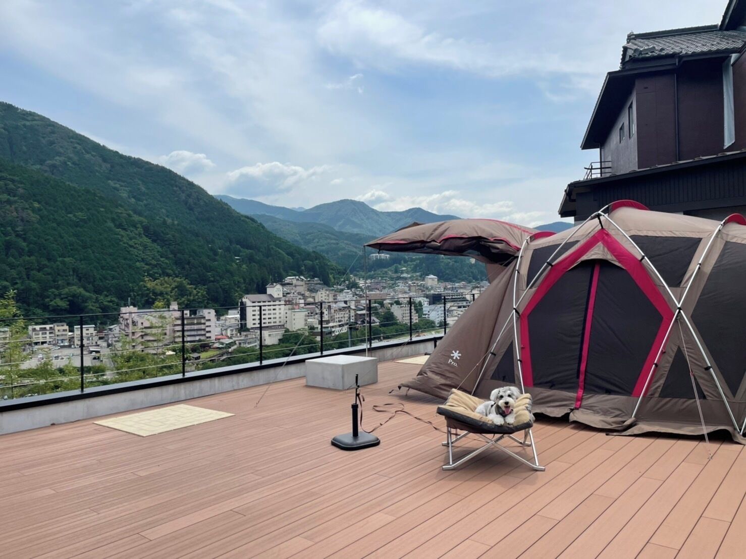 Terraço no terraço com uma tenda e uma cama para cachorro, com vista para uma cidade e montanhas.