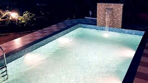 Uma banheira de hidromassagem retangular com borda em azulejo, rodeada por um padrão de piso xadrez.