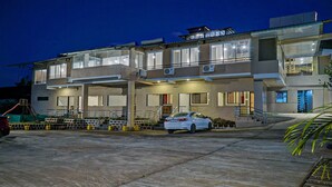 Um edifício de vários andares com um carro estacionado em frente.