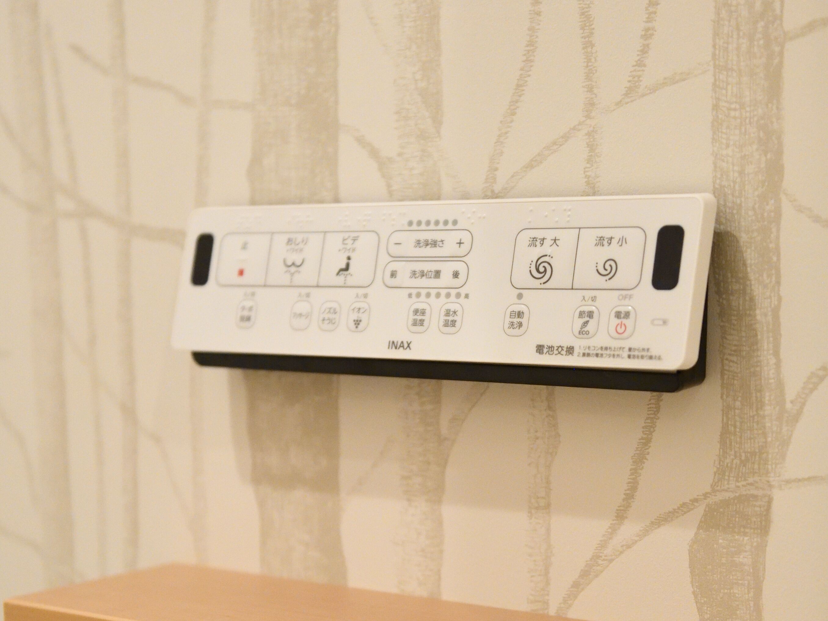 Painel de controle com texto e símbolos em japonês, provavelmente para os serviços de um quarto de hotel.