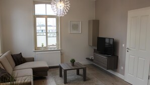 Uma sala de estar com sofá, mesa de centro, televisão e radiador.