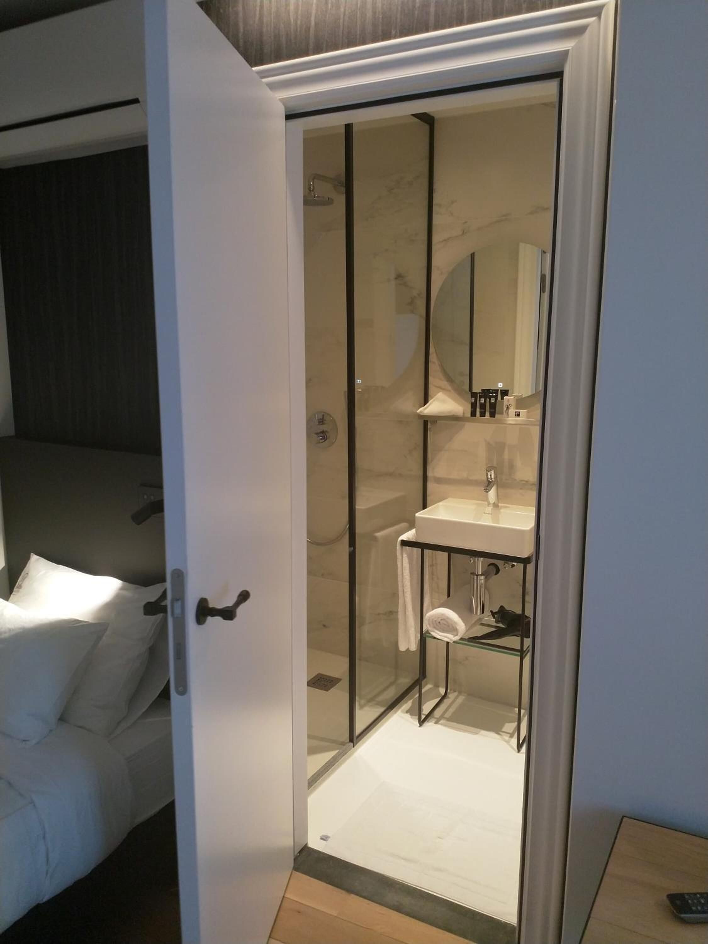 Casa de banho moderna com cabine de chuveiro em vidro, lavatório branco e espelho sobre o lavatório.