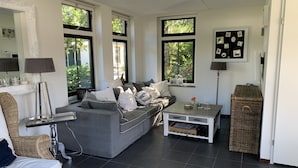 Uma sala de estar moderna com um sofá cinza, uma mesa de centro e uma cesta de vime.